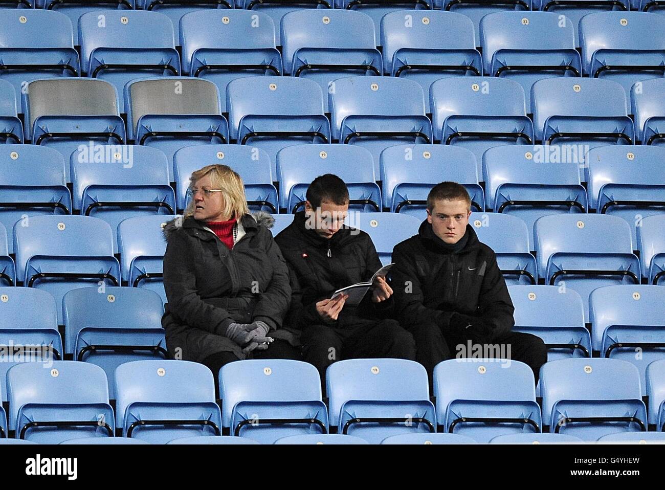 Football fans sit in the stands surrounded by empty seats hi-res stock ...