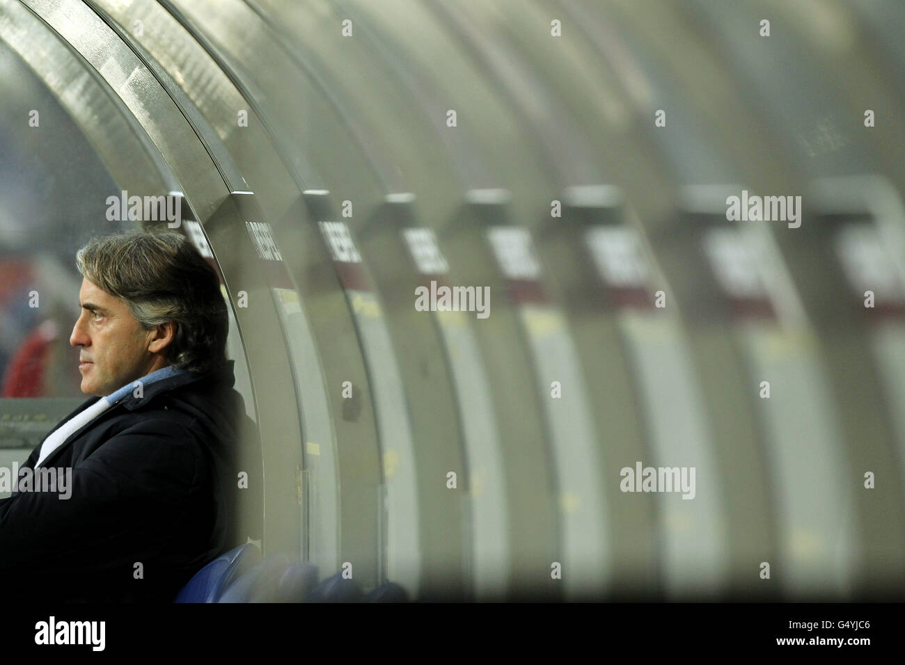 Manchester city manager roberto mancini sits on his team bench hi-res ...