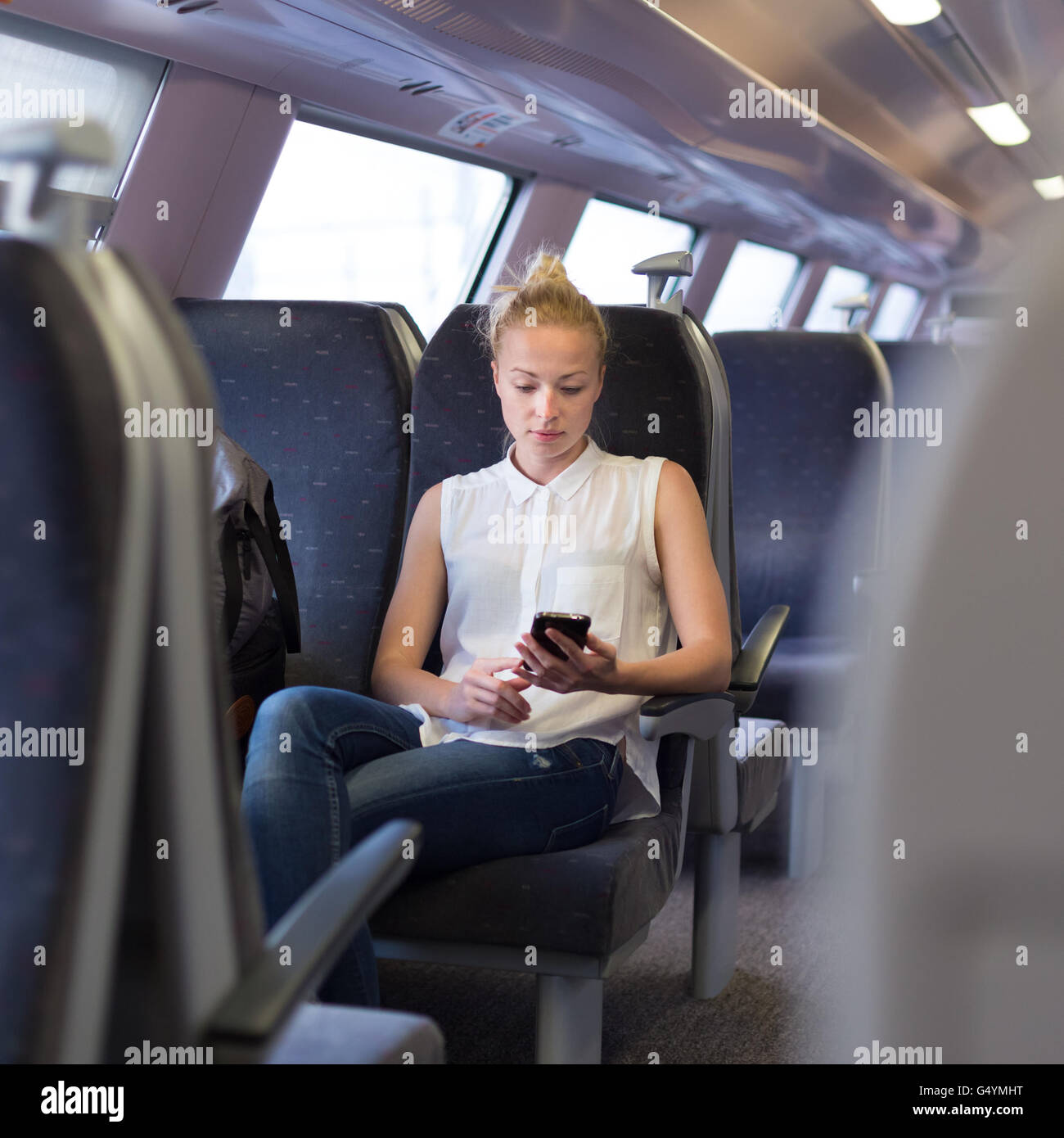 Woman using mobile phone while travelling by train Stock Photo - Alamy