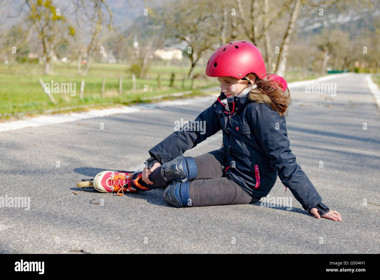 young attractive teenage skater grimacing in pain after taking a fall ...