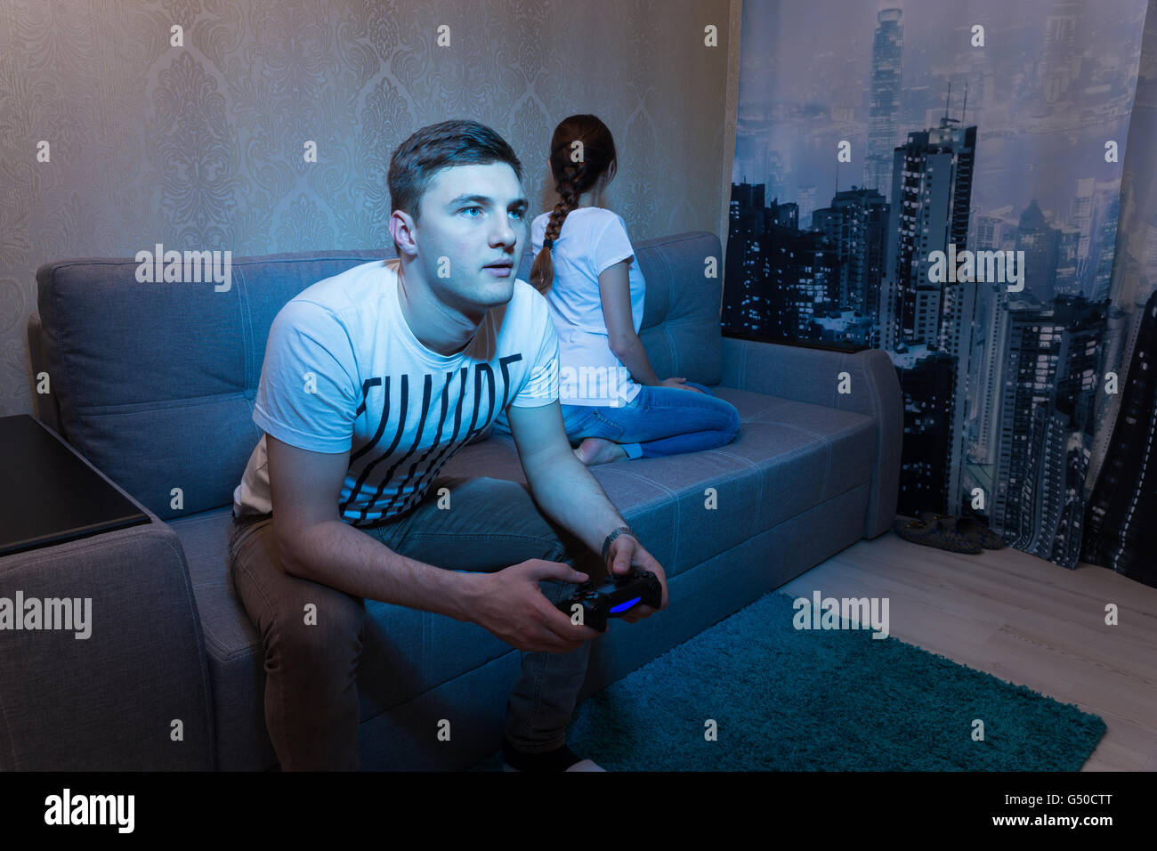 Concentrated young man playing a video game holding a console sitting ...
