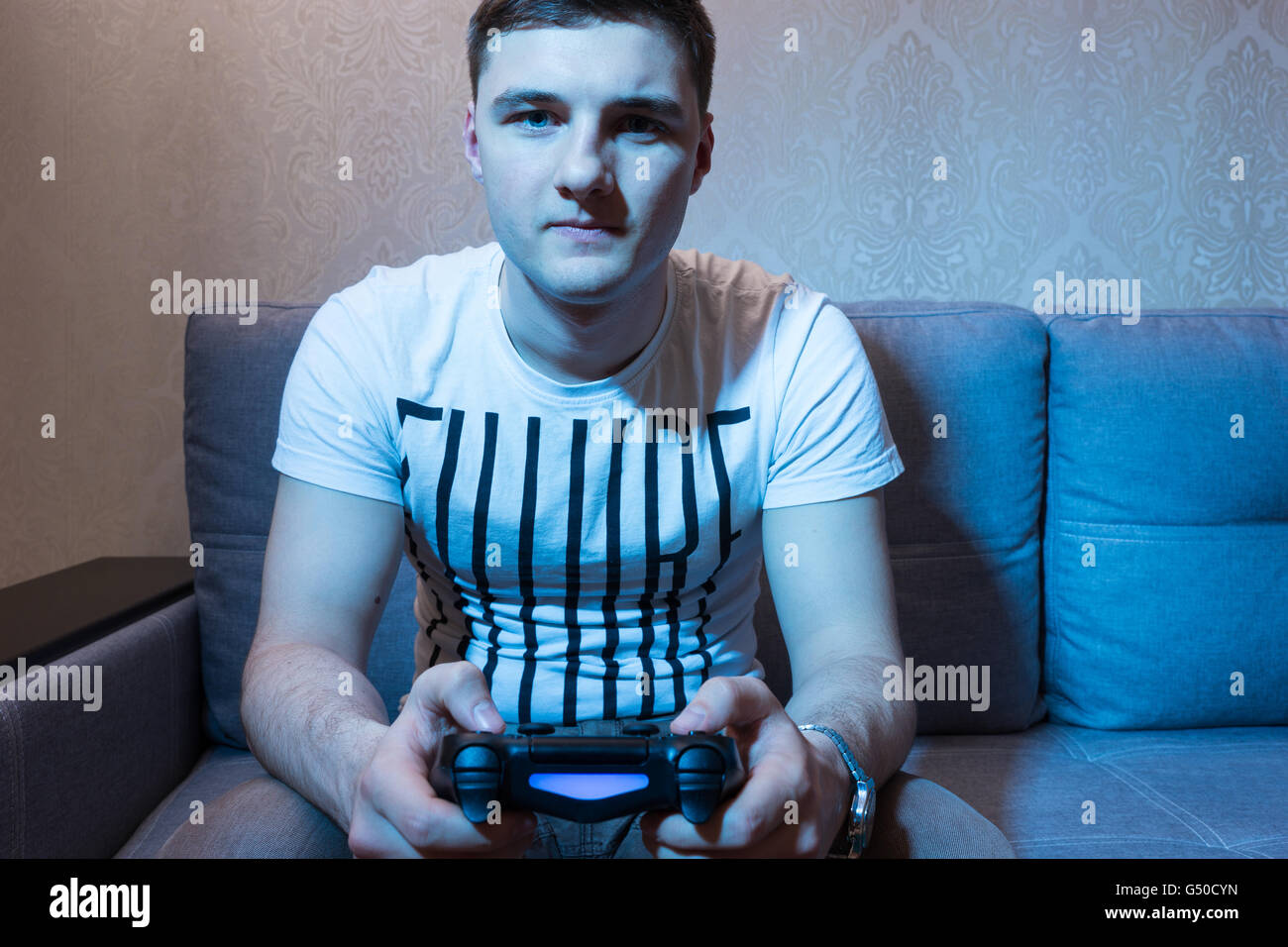Addicted fashionable young man playing a video game with a very serious ...