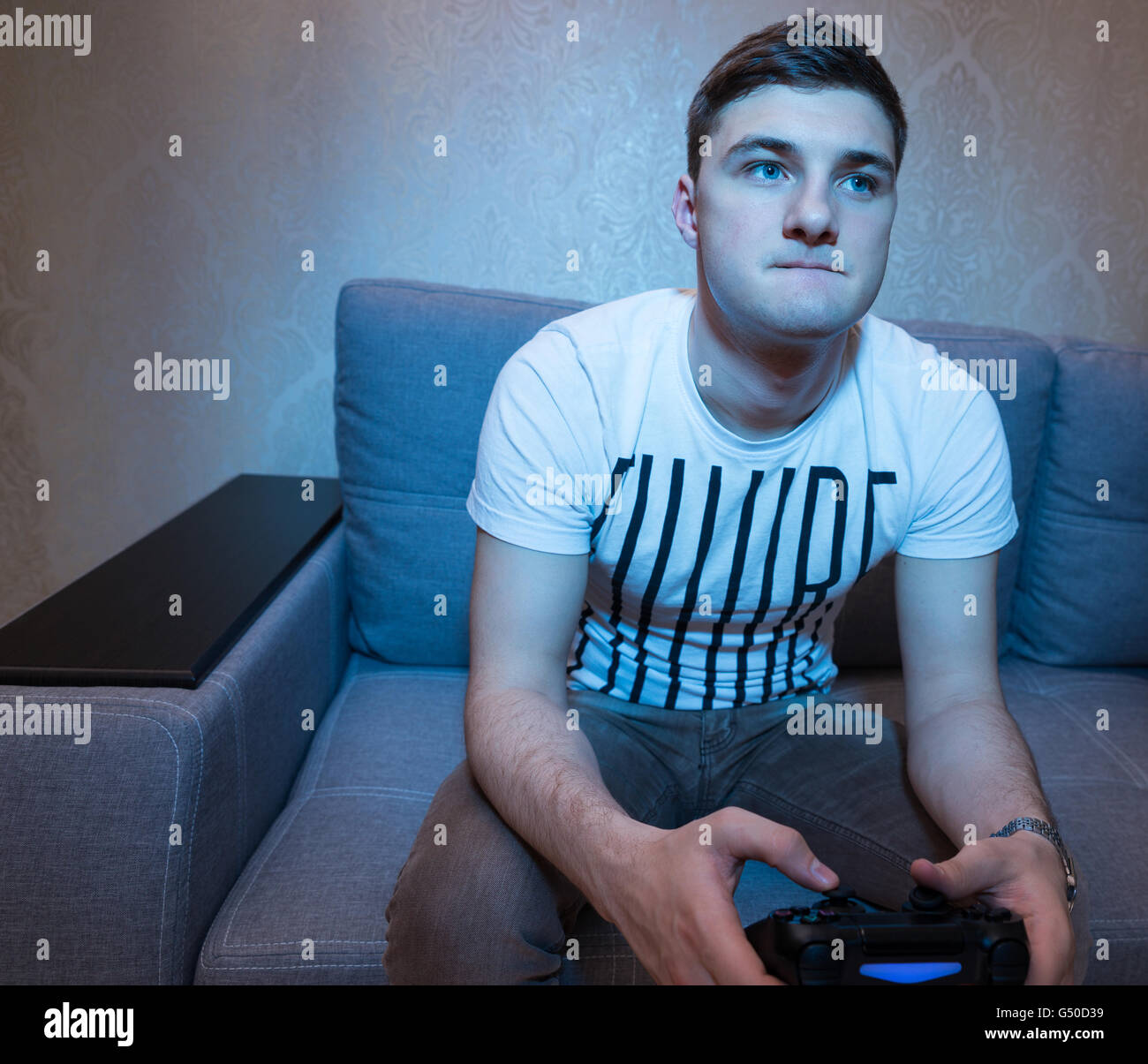 Male gamer playing a video game with a very serious and concentrated ...