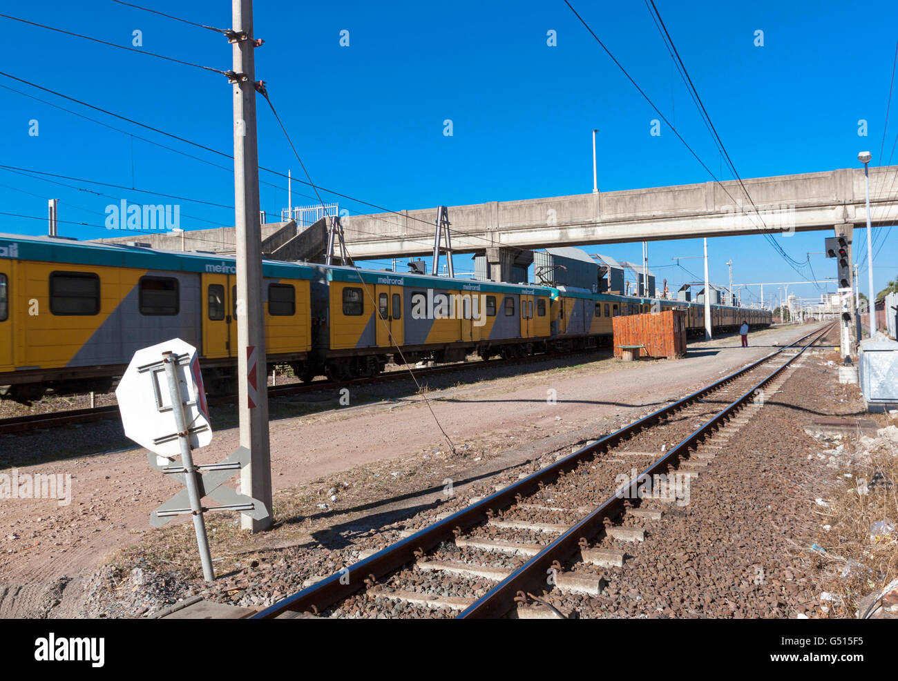 Yellow metro train passing security guard under bridge heading toward ...