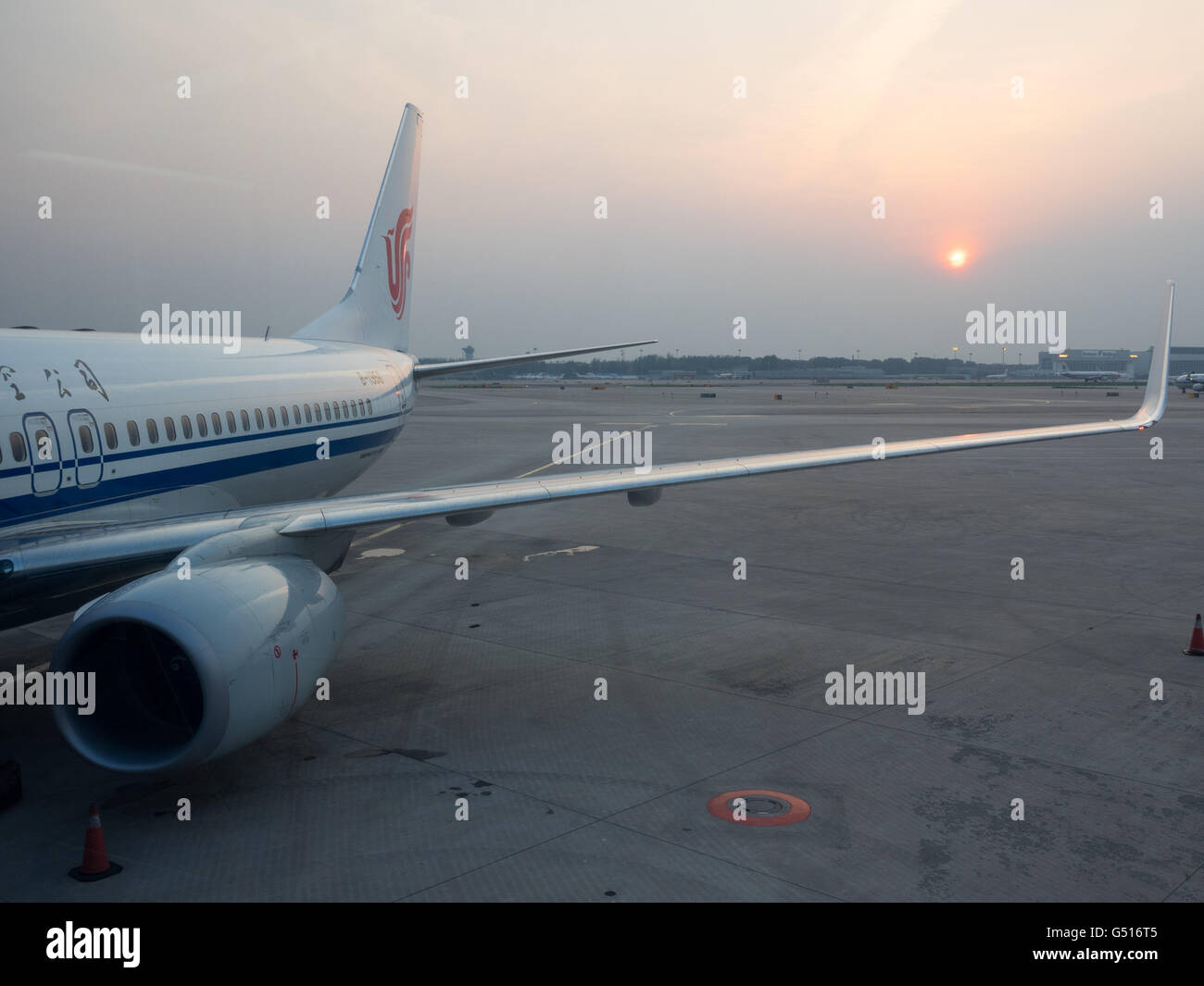 China, Beijing, plane at the International Airport with the sun setting ...