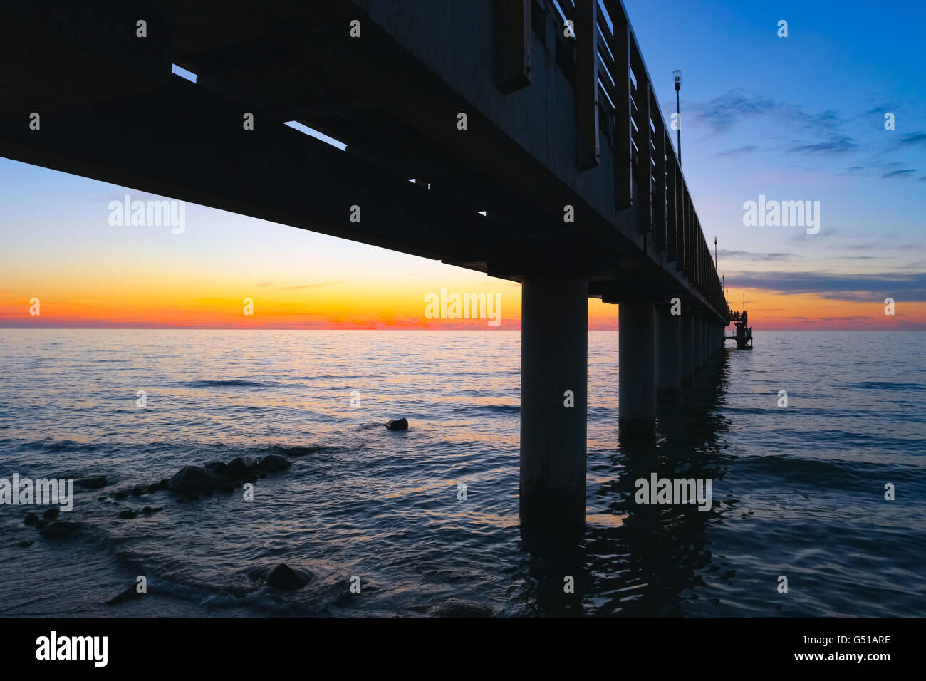 Long sea pier and beach at sunset Stock Photo - Alamy