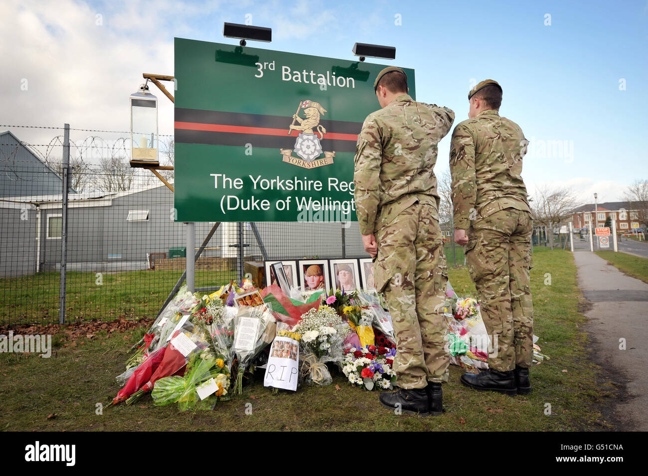 Soldiers salute after placing pictures among floral tributes at the 3rd ...
