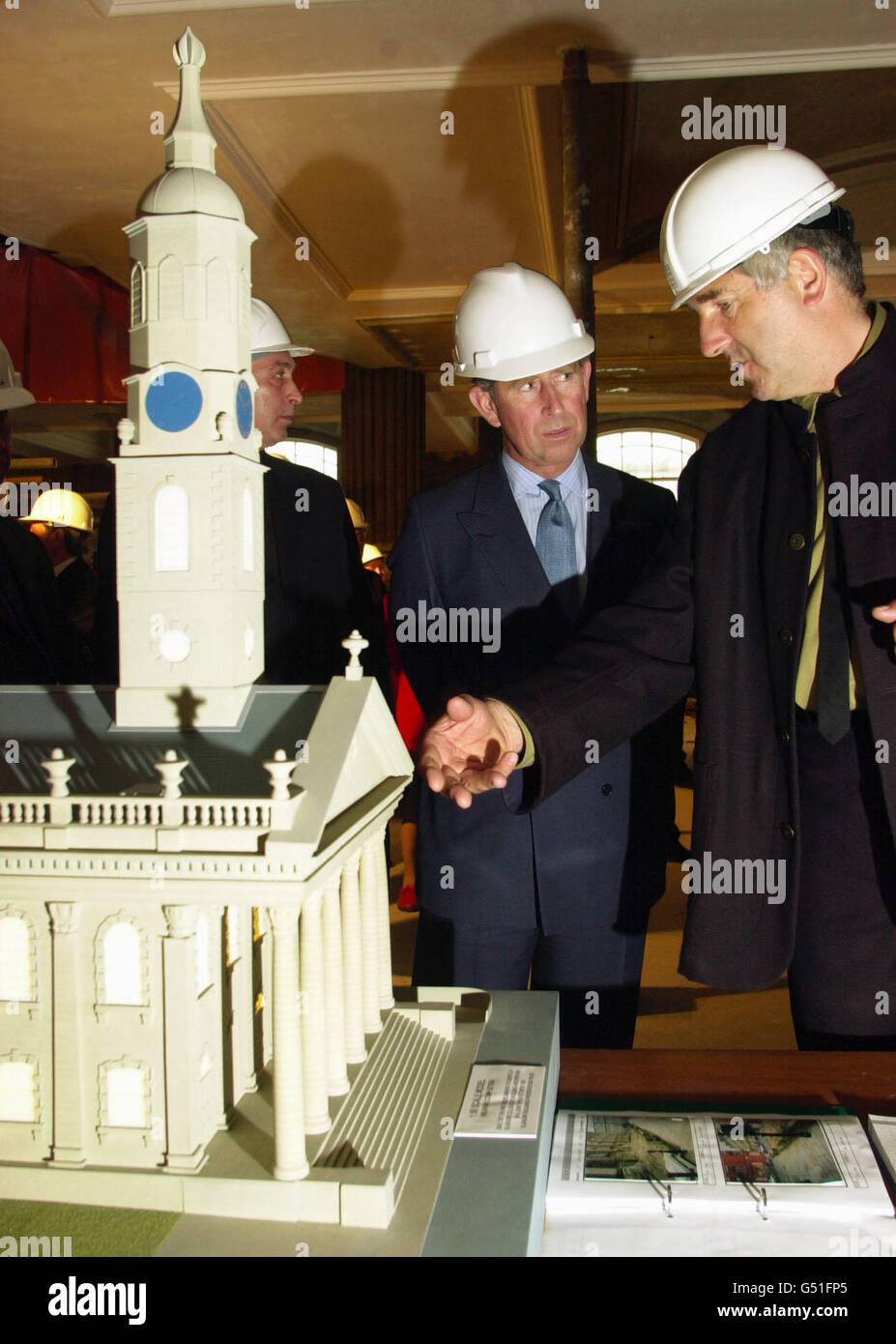 The Prince of Wales (centre) is shown a model of the restoration plan ...