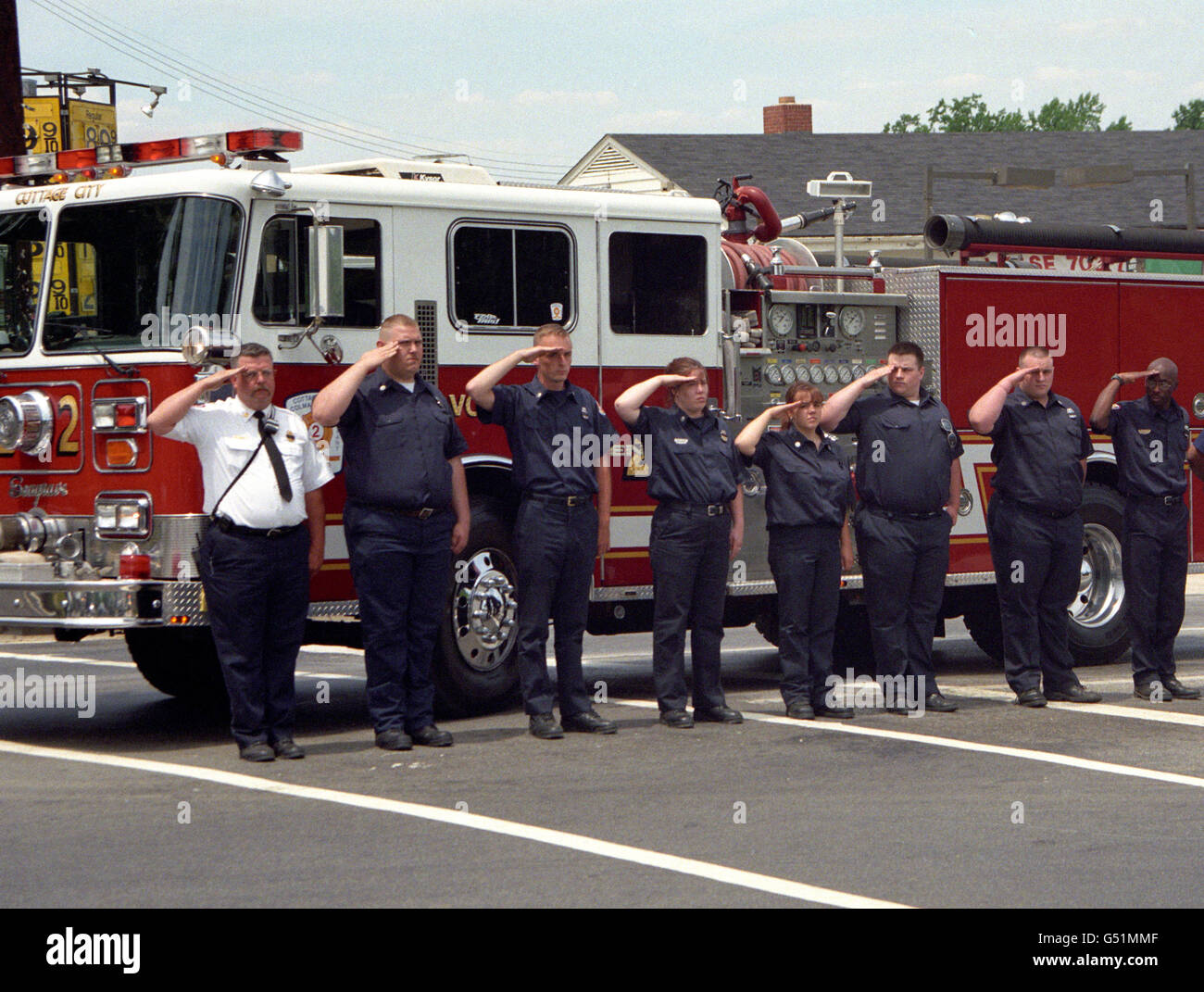 Firefighters stand at attention as a hearse containing the body of a ...