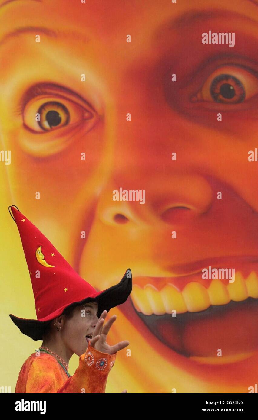 A festival goer dances in front of a huge painted face backdrop at the ...