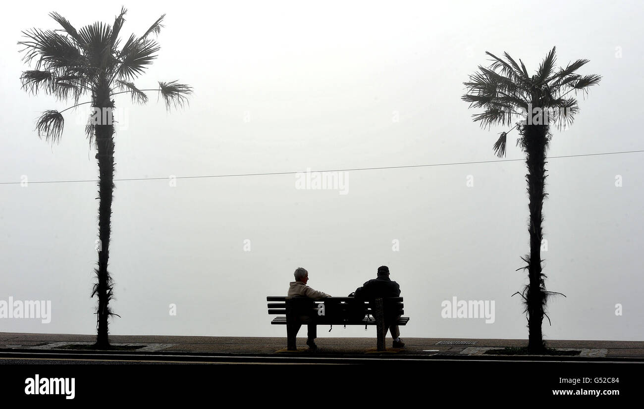 A couple sit on a fog shrouded sea front bench, waiting for the ...
