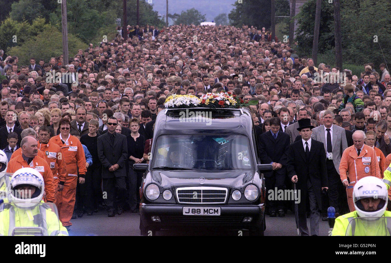 Thousands of Mourners walk behind the hearse carrying the coffin of ...