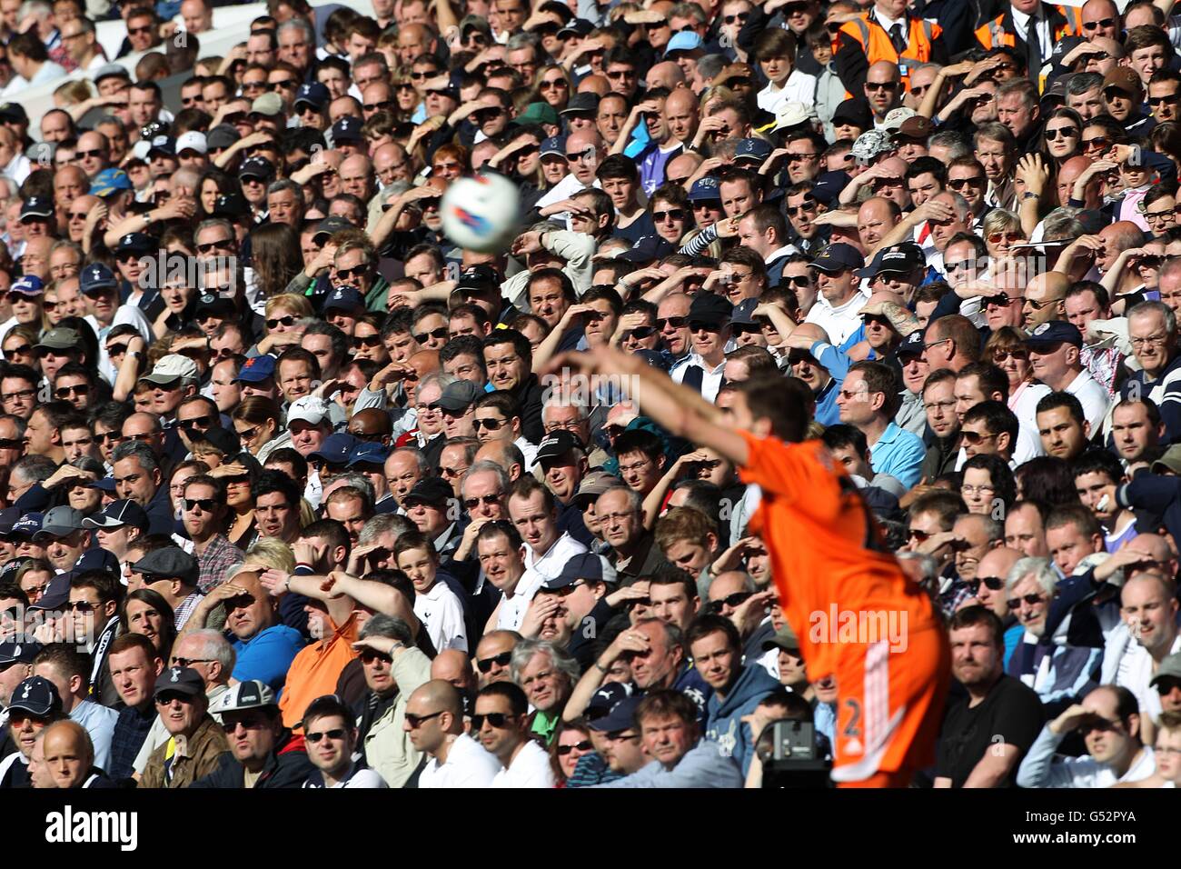 Fans in the stands shield their eyes from the sun as they keep an eye ...