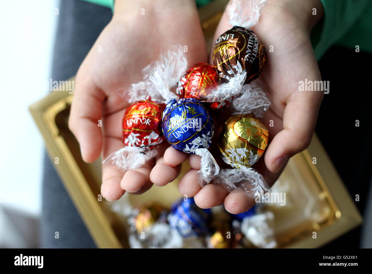 Close up of hand holding Assorted Lindt Lindor Chocolates in metallic ...