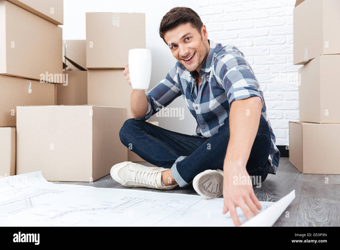 Happy handsome man looking at house construction plan indoors Stock ...