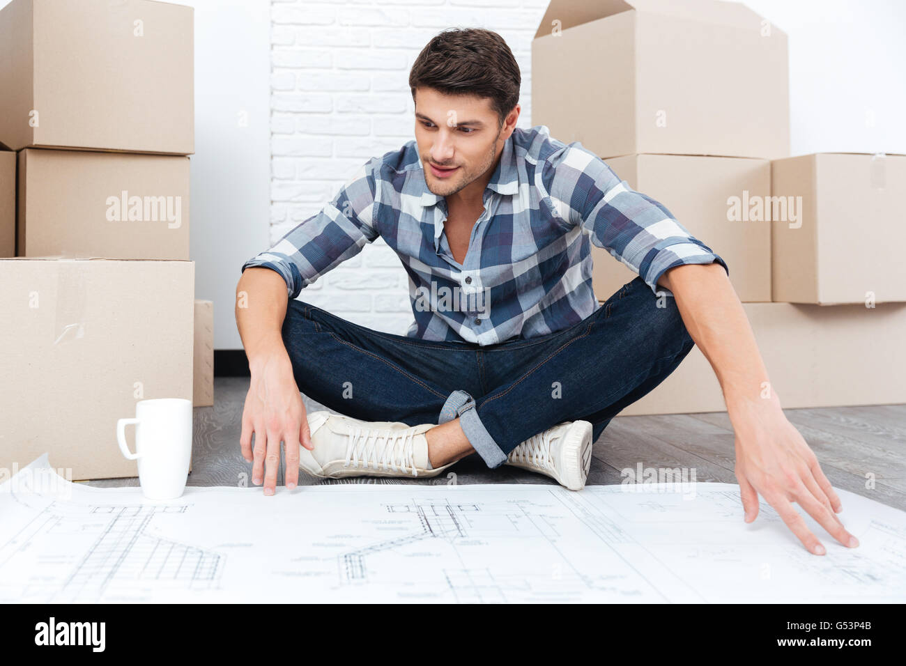 Handsome man looking at the house plan blueprint indoors Stock Photo ...