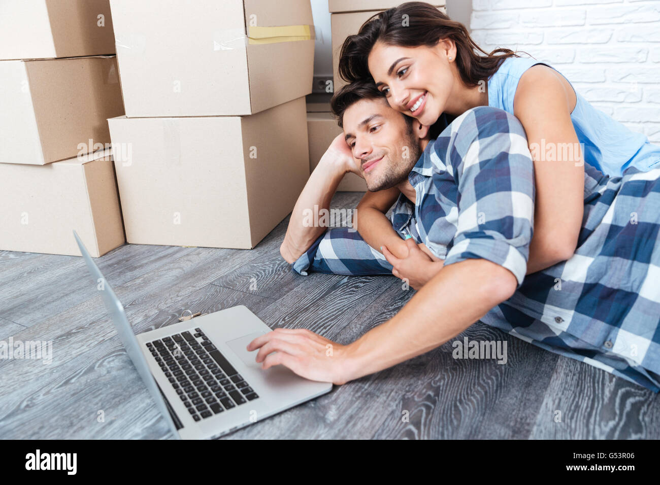 Young smiling couple using laptop computer in their new house Stock ...