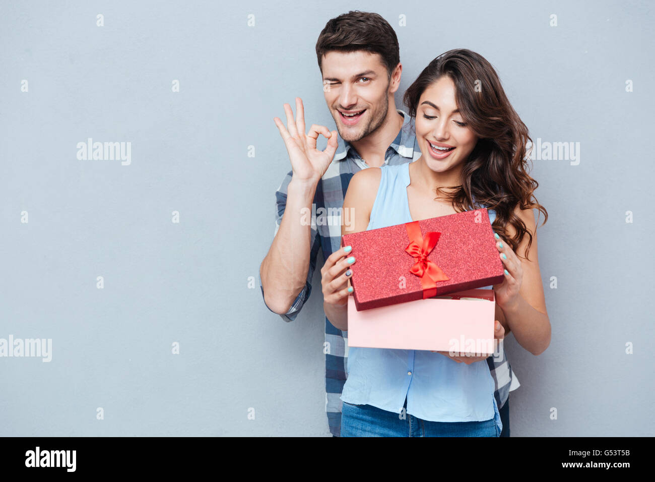 Young beautiful woman receiving a gift from her boyfriend showing ok ...