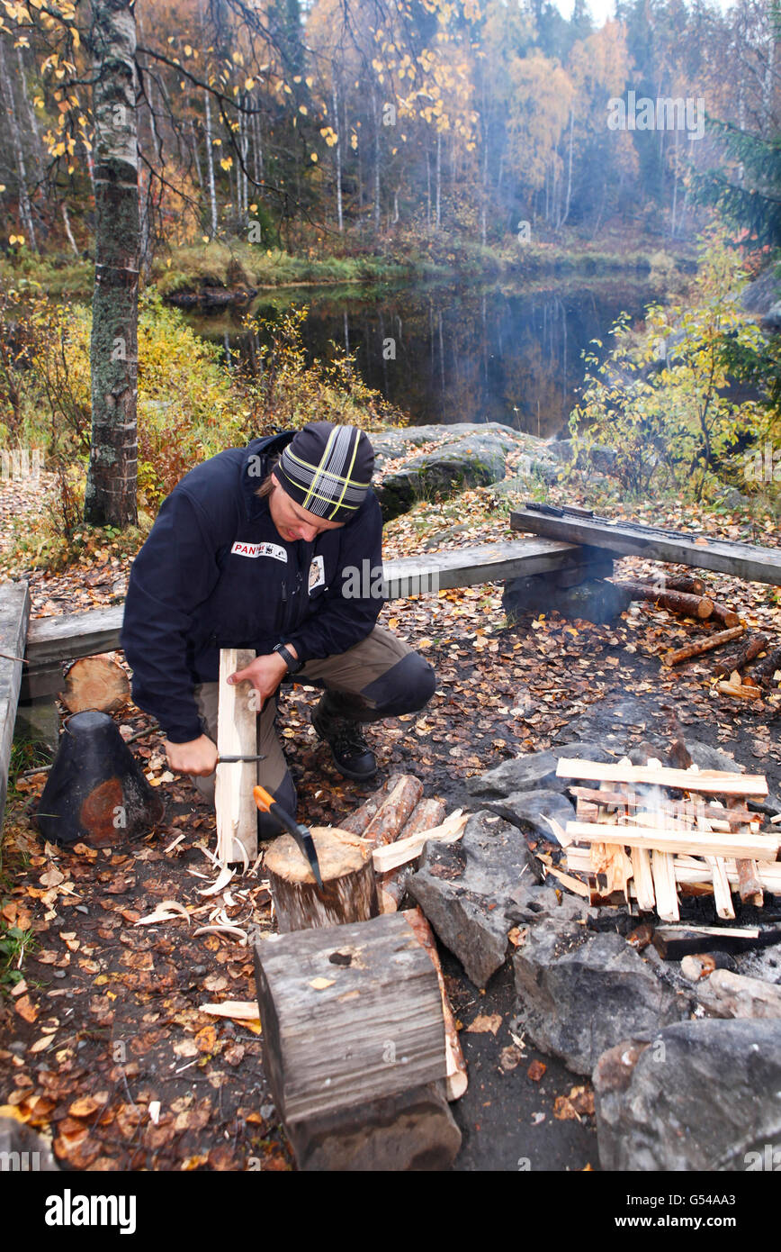 Finland; Karhunkierros Trail - the great bear trail hike in Lapland, a hiker cutting wood in ...