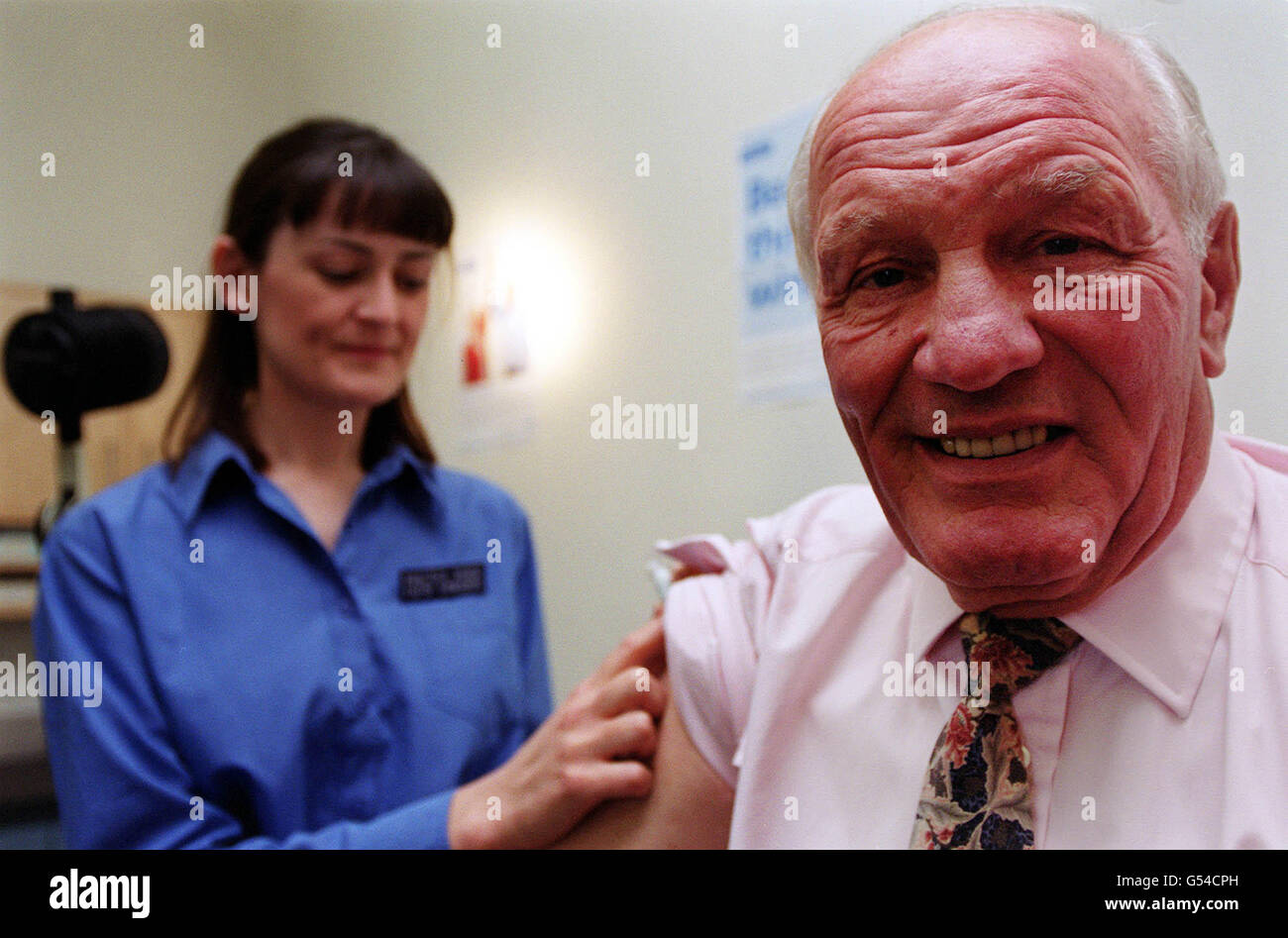 Sir Henry Cooper receives a flu jab from Practice Nurse Faith Edwards ...