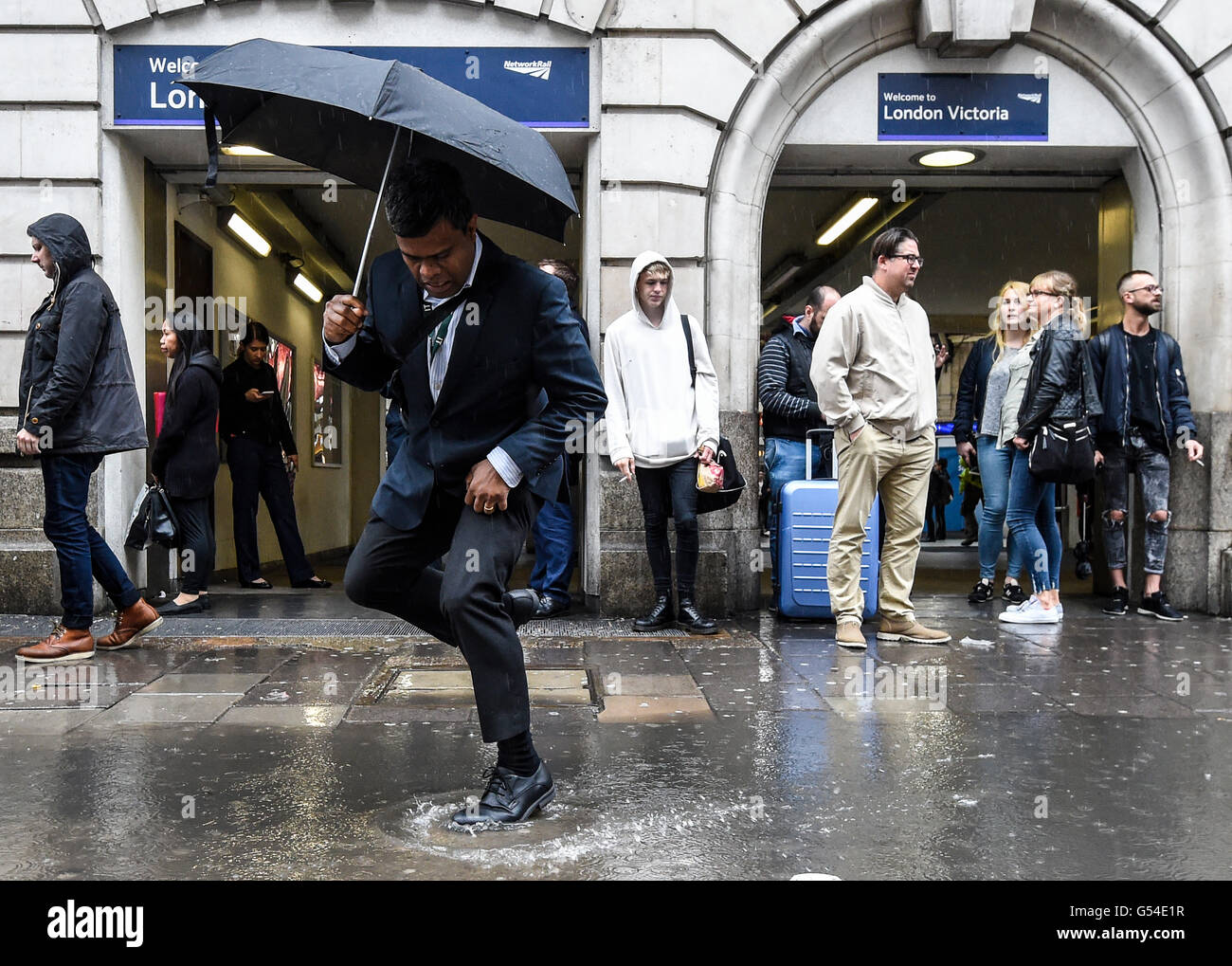 People attempt to avoid a large puddle outside Victoria Station in ...