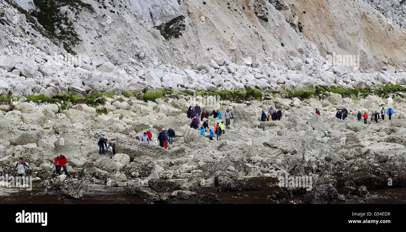 Walkers scramble over rocks as they head for the Lighthouse at Beachy ...