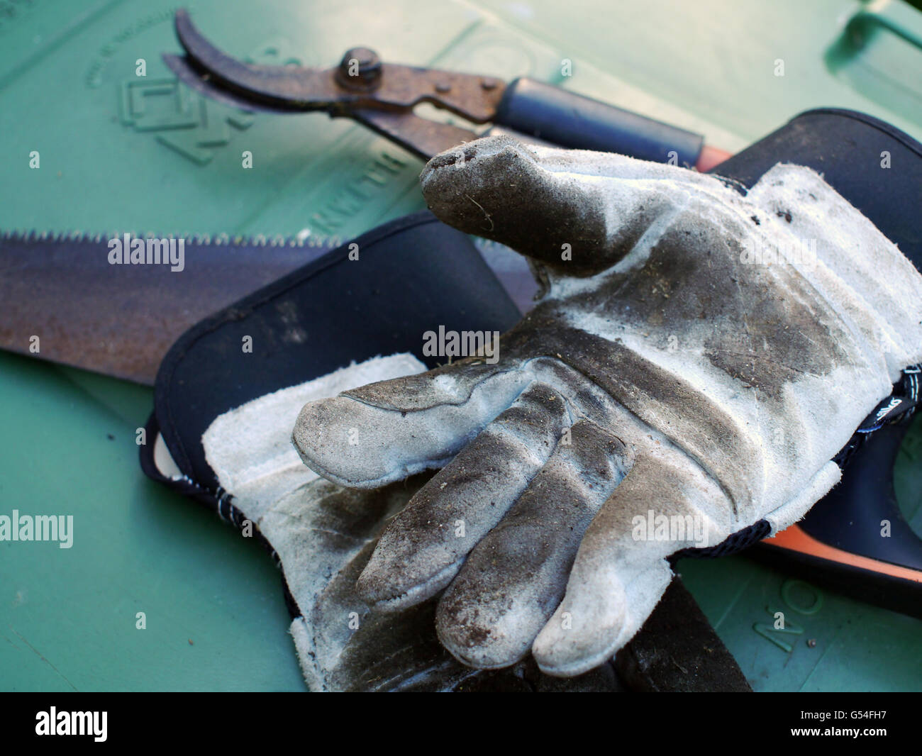 Garden gloves with tools on waste bin lid Stock Photo - Alamy