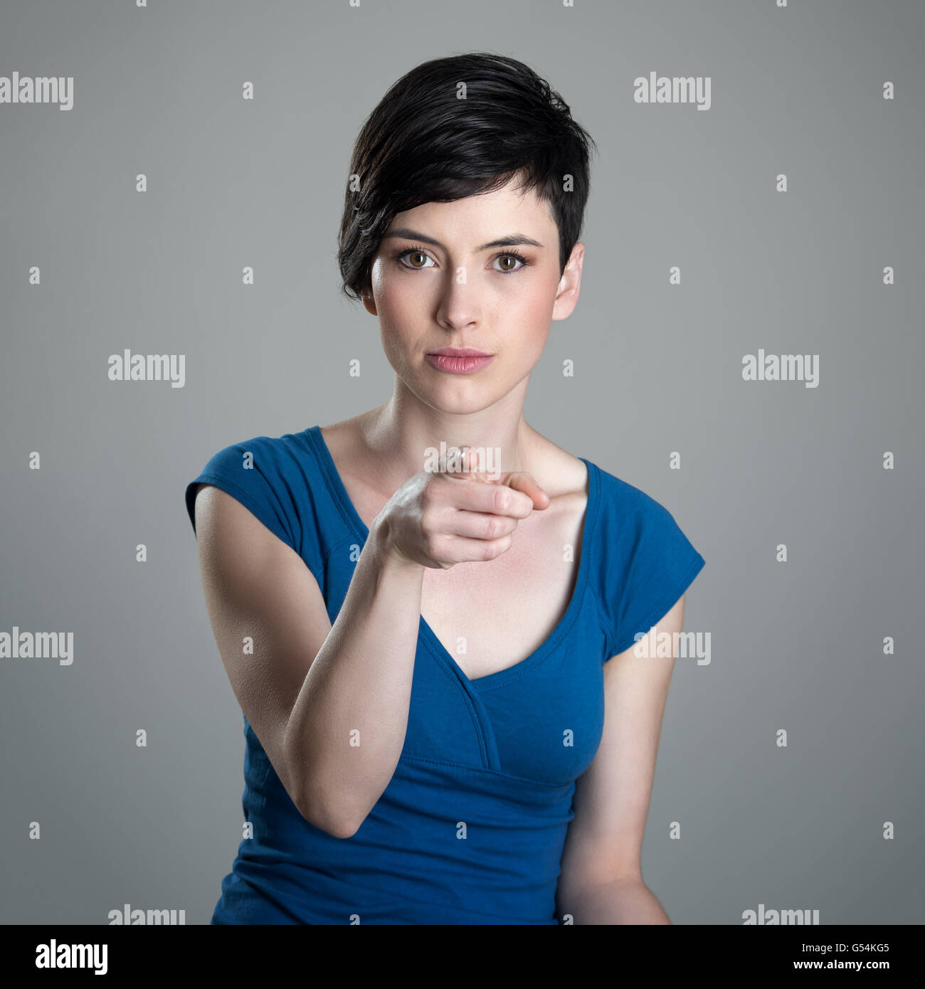 Young short hair woman pointing finger at camera accusing or blaming ...