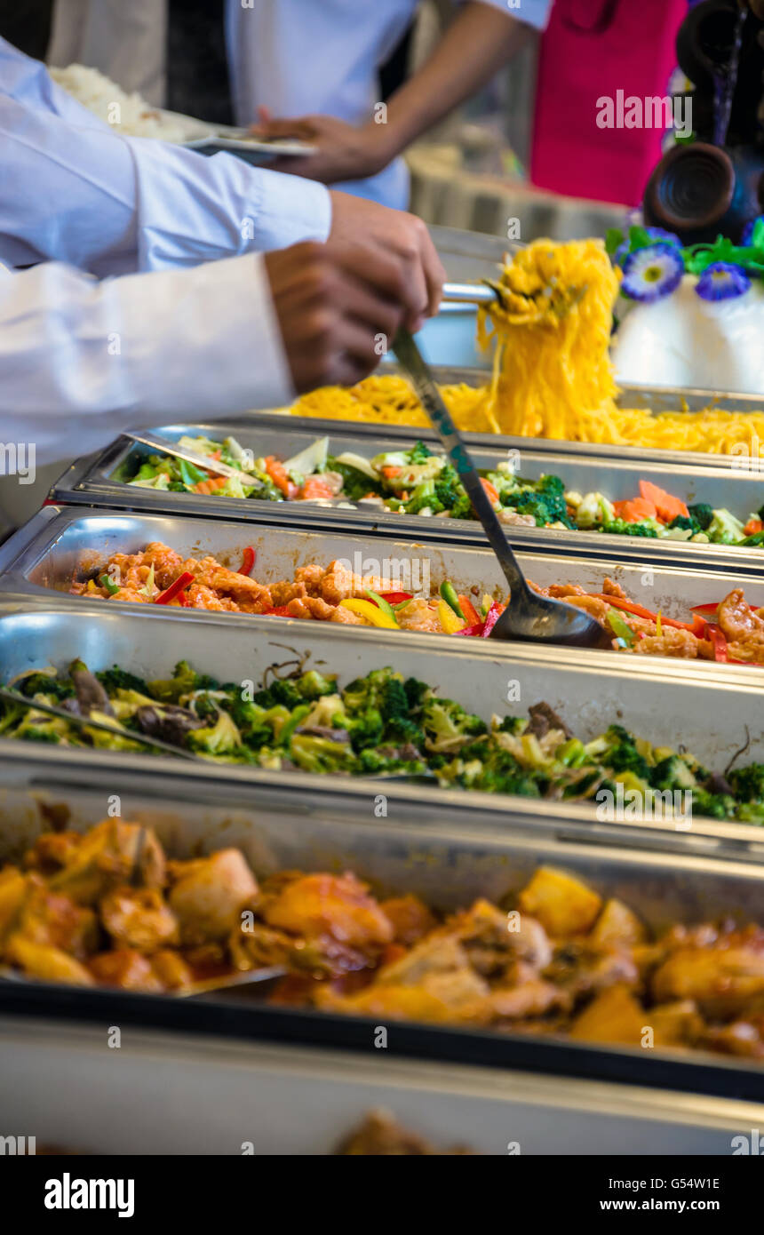 People help themselves to food at a self-service buffet at a party ...