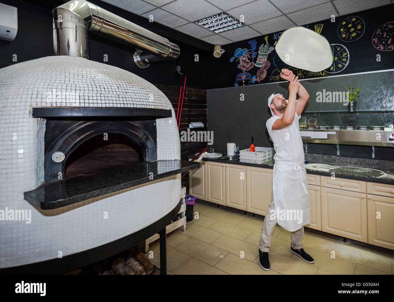 Bearded pizza chef play with pizza dough in traditional restaurant ...