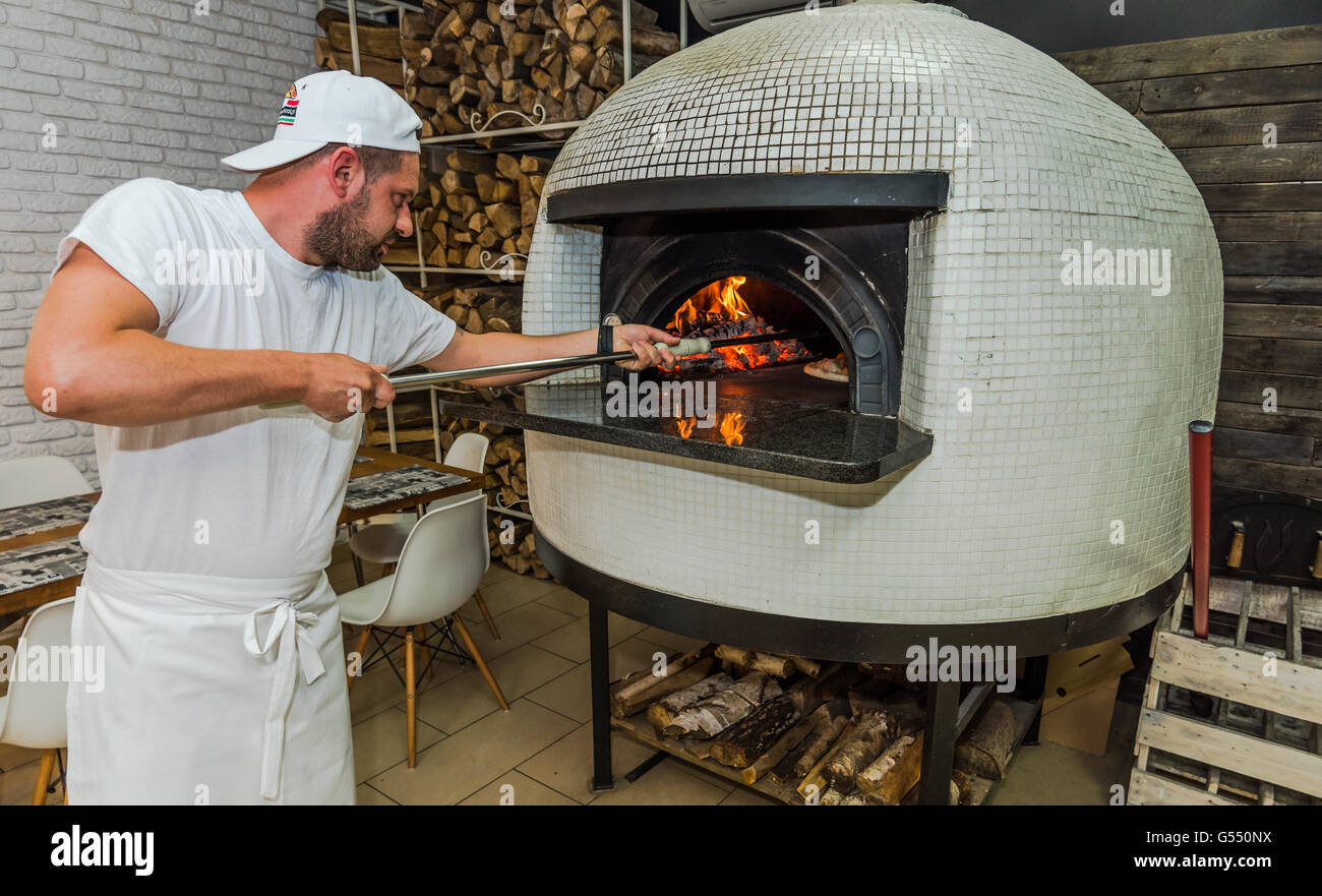 Young kitchen chef check pizza in traditional wood fired oven Stock ...
