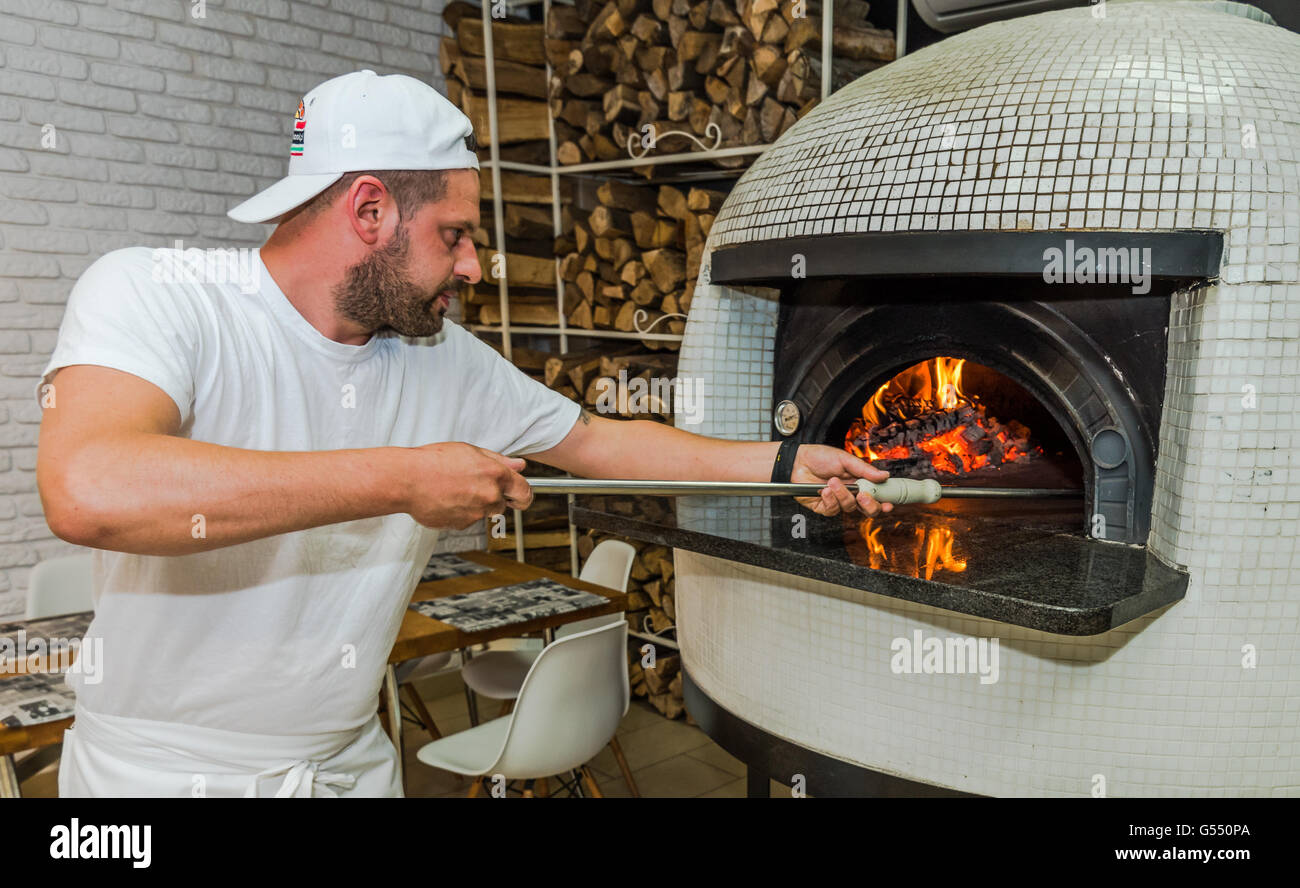 bearded young man check on pizza in wood fired oven Stock Photo - Alamy