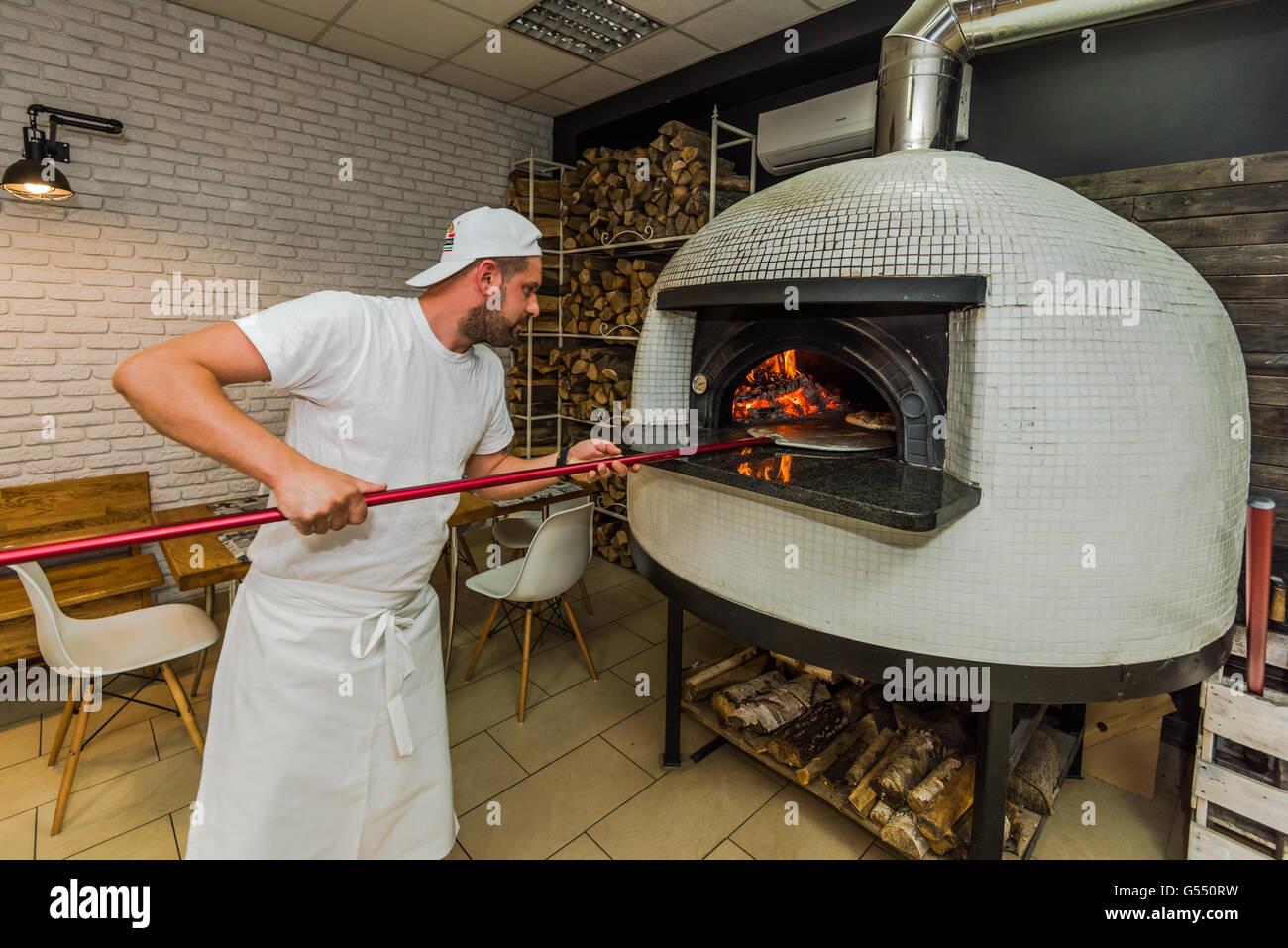 bearded young man check on pizza in wood fired oven Stock Photo - Alamy