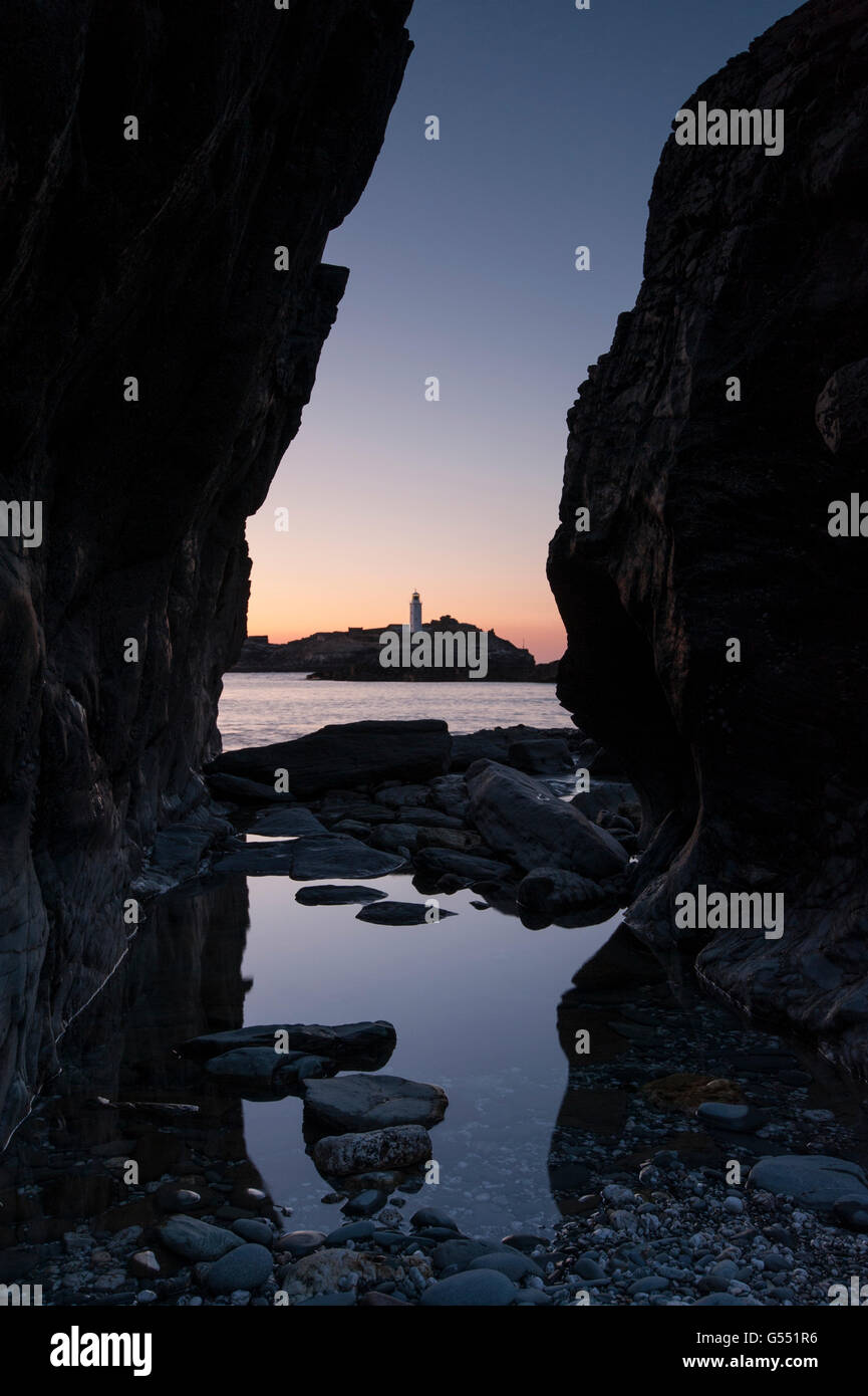 View of Godrevy Lighthouse between two rock faces at dusk Stock Photo ...