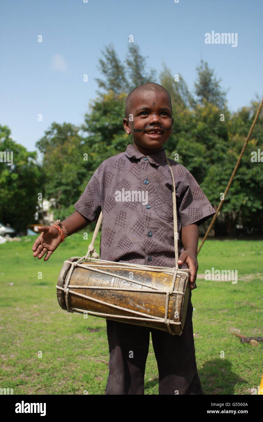 A poor Indian boy playing a traditional Indian drum for making money ...