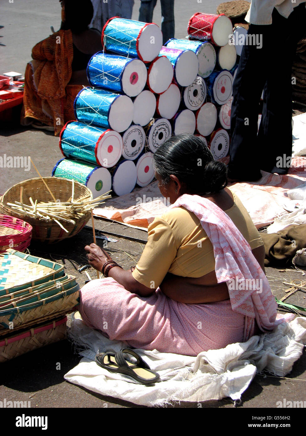 A poor woman selling handmade cane baskets in her streetside shop in ...
