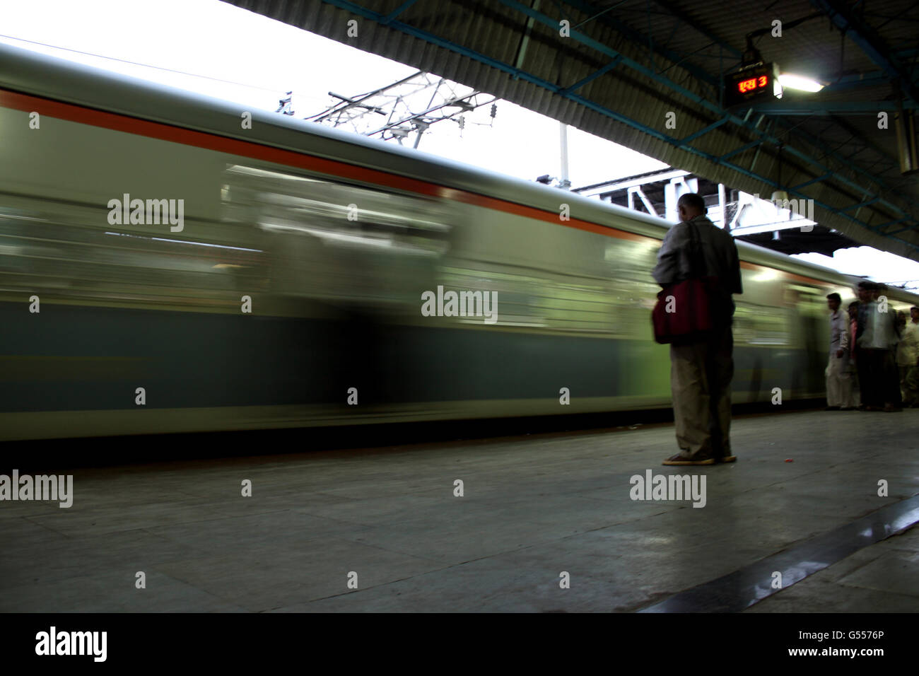 A commuter waiting for his train to arrive at an Indian railway station ...