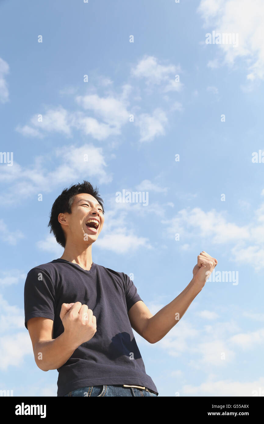 Young Japanese man cheering against blue sky Stock Photo - Alamy