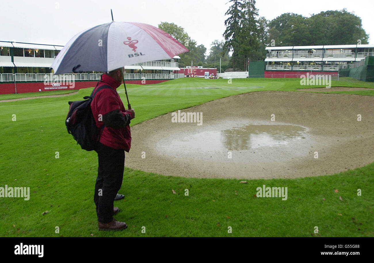 SSpectators look at the rain-filled bunker at the 18th green at the ...