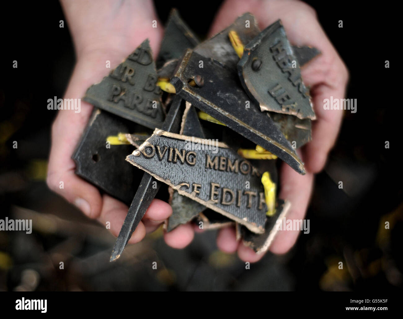 A woman holds broken memorial plaques as metal seized by police ...