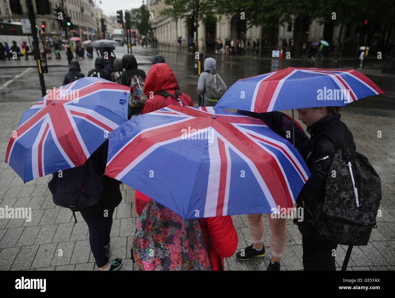 People shelter under umbrellas in central London, as heavy rain and ...