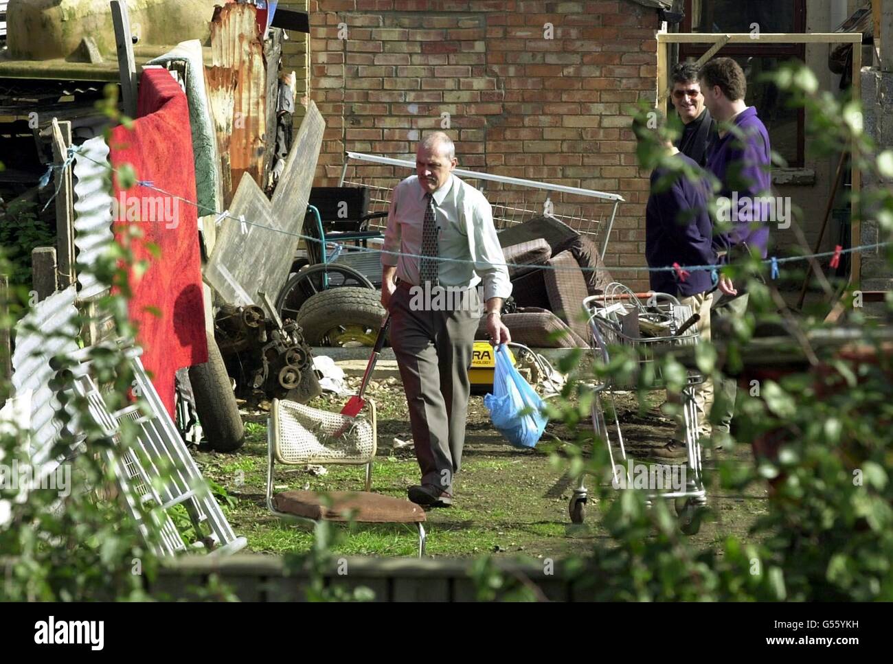 Policeman uses a probe to search the back garden in one of the houses ...