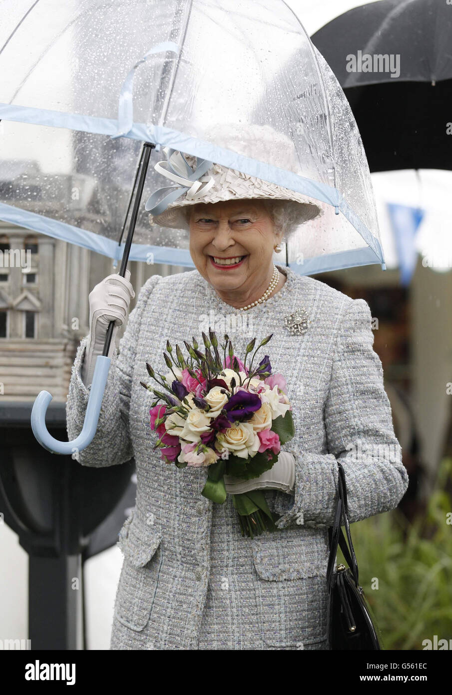 Queen Elizabeth II shelters under an umbrella during her visit to the ...