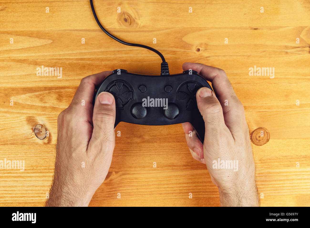 Hands using gamepad controller on wooden desk, flat lay top view ...