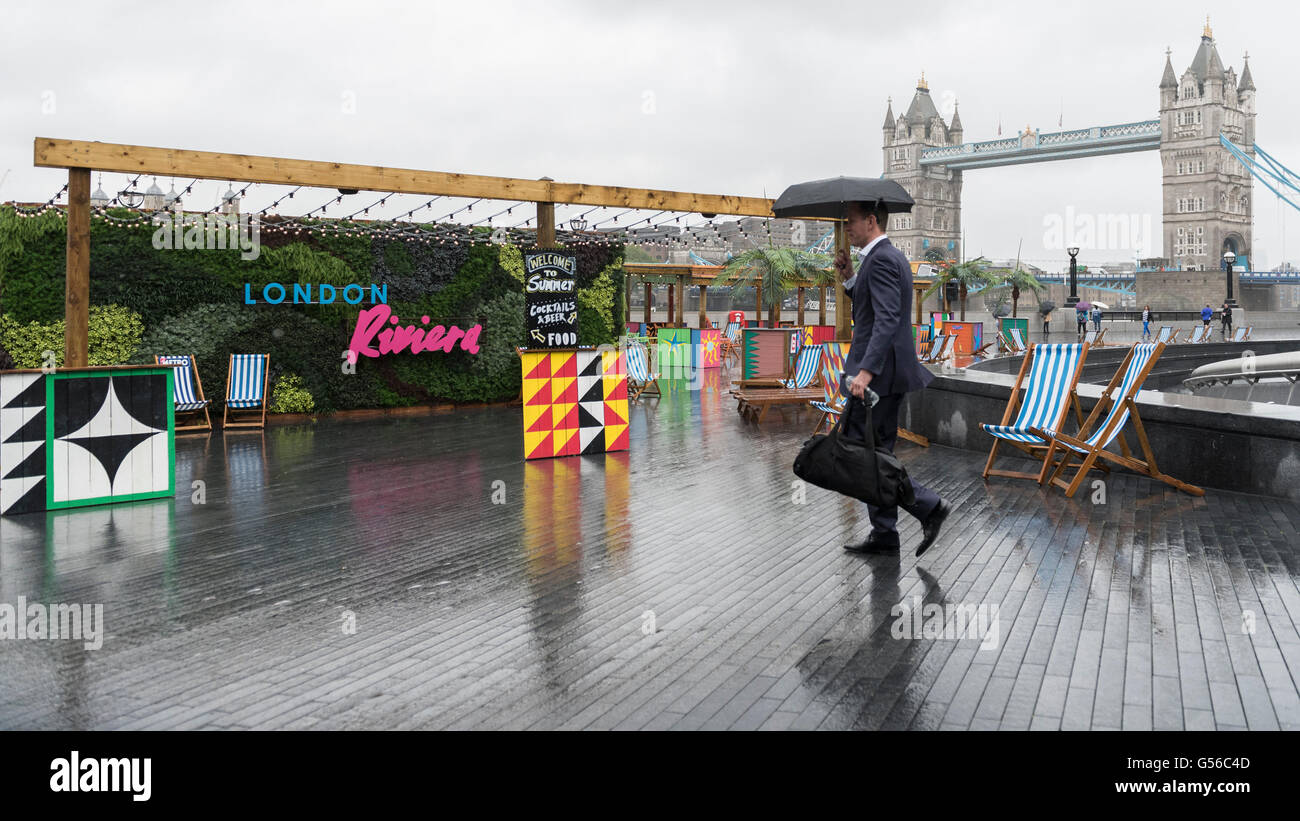London, UK. 20 June 2016. A commuter walks by in heavy rain pouring ...