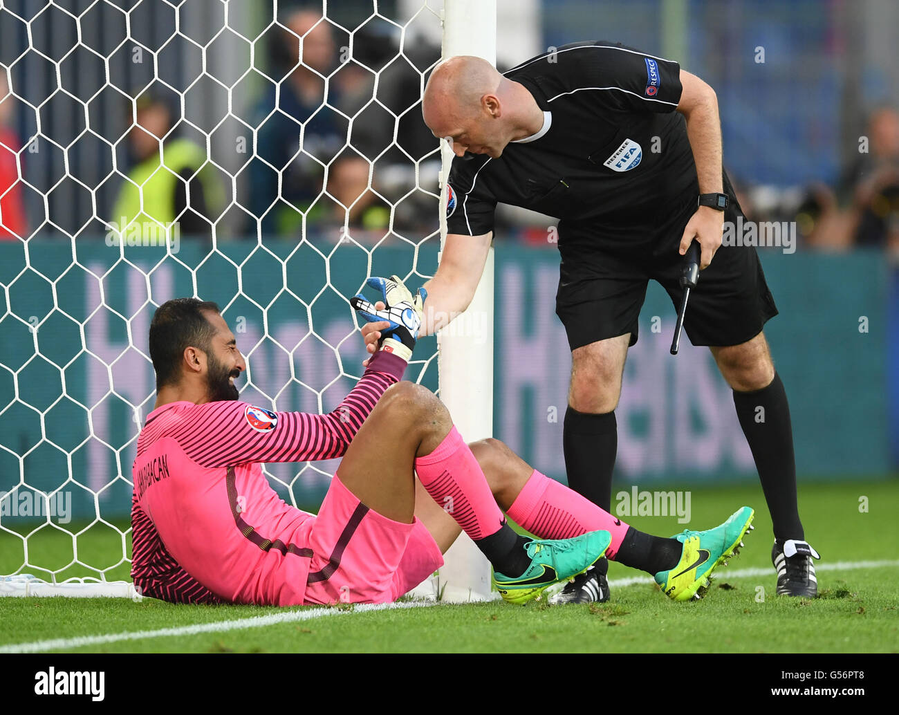 Assistant referee Bobby Madden (R) of Scotland helps goalkeeper Volkan ...