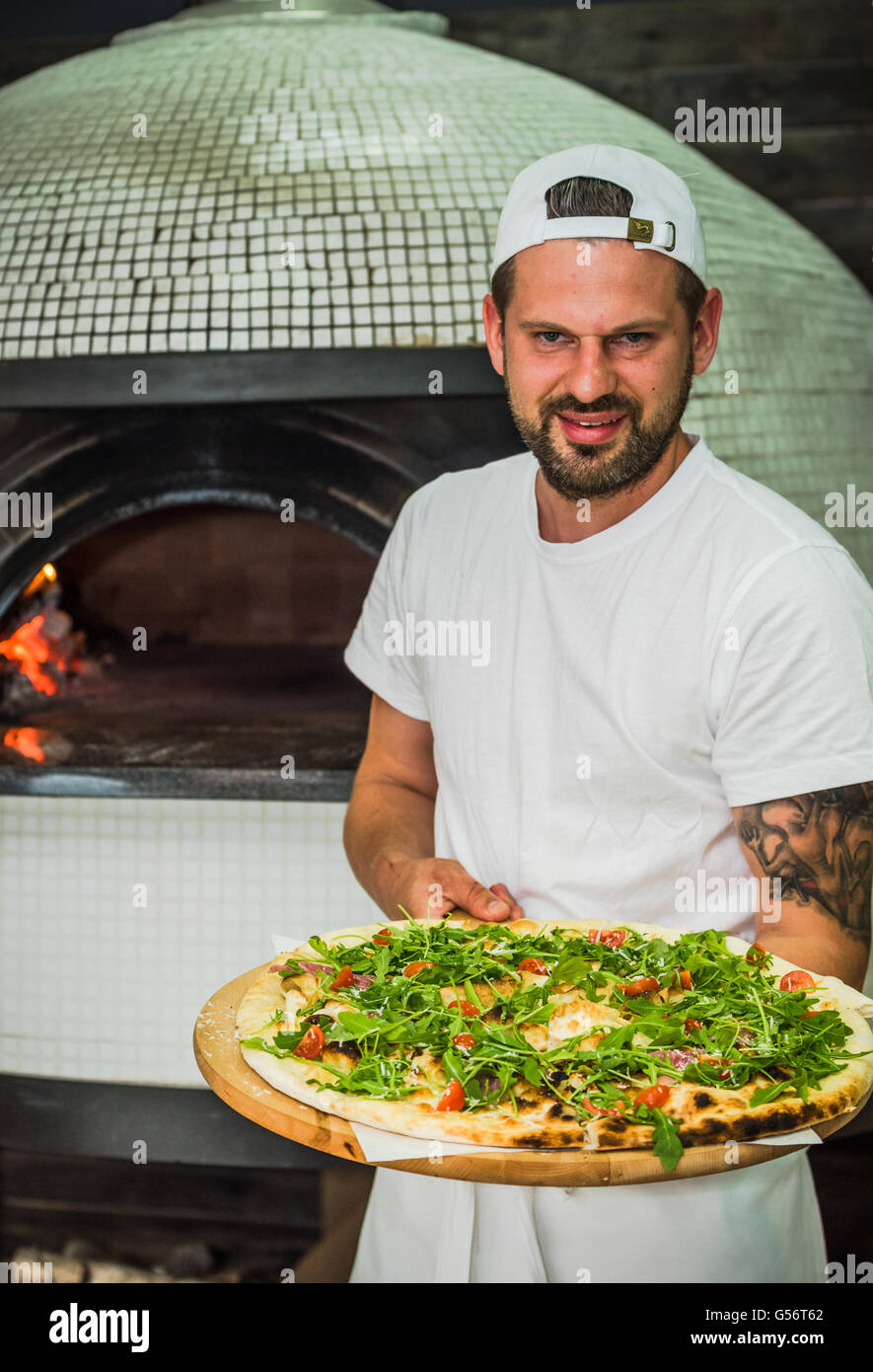 smiling young chef show off pizza in traditional restaurant Stock Photo ...
