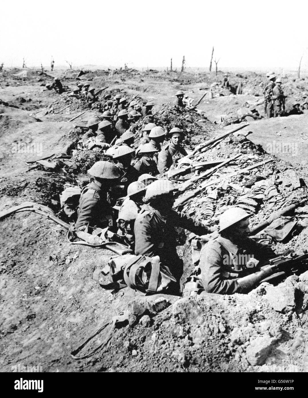 British infantrymen occupy a shallow trench in a ruined landscape ...