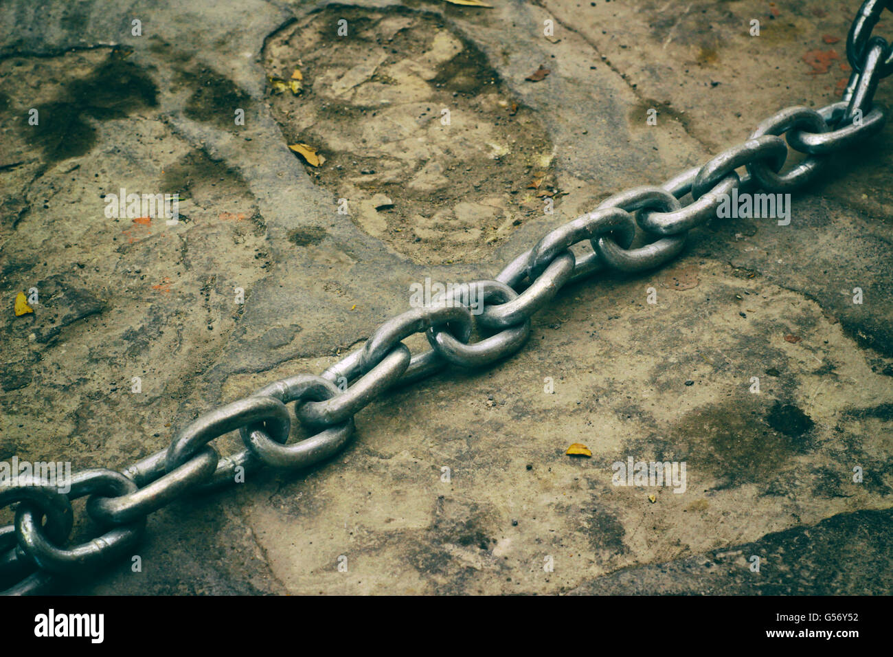 Photograph of a metal steel chain on a stone floor Stock Photo - Alamy