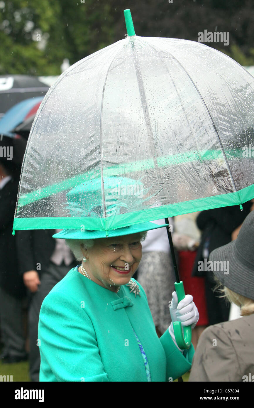 Britain's Queen Elizabeth II shelters from the rain under an umbrella ...